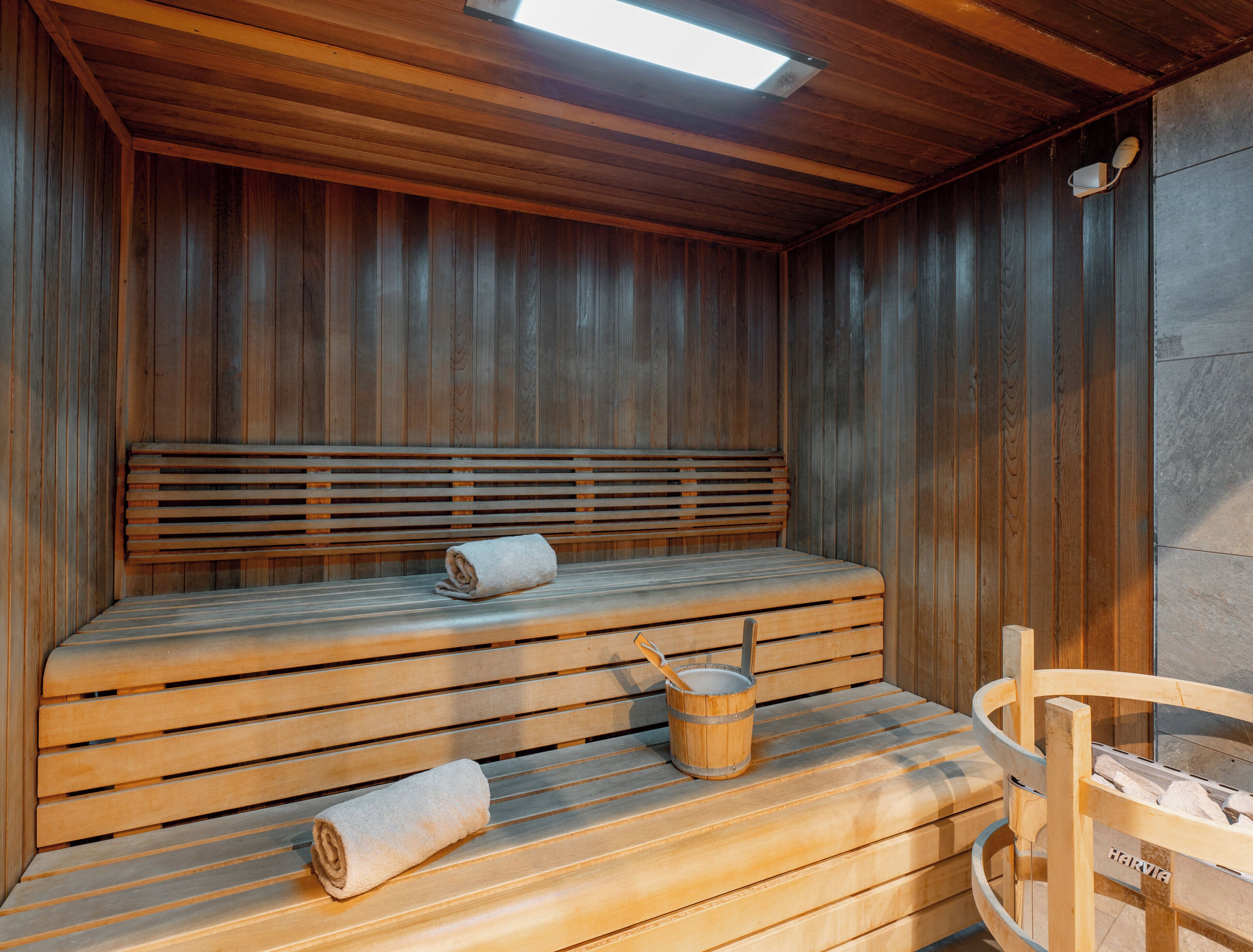 Uma sauna com bancos de madeira, aquecedor para bancos e um balde.