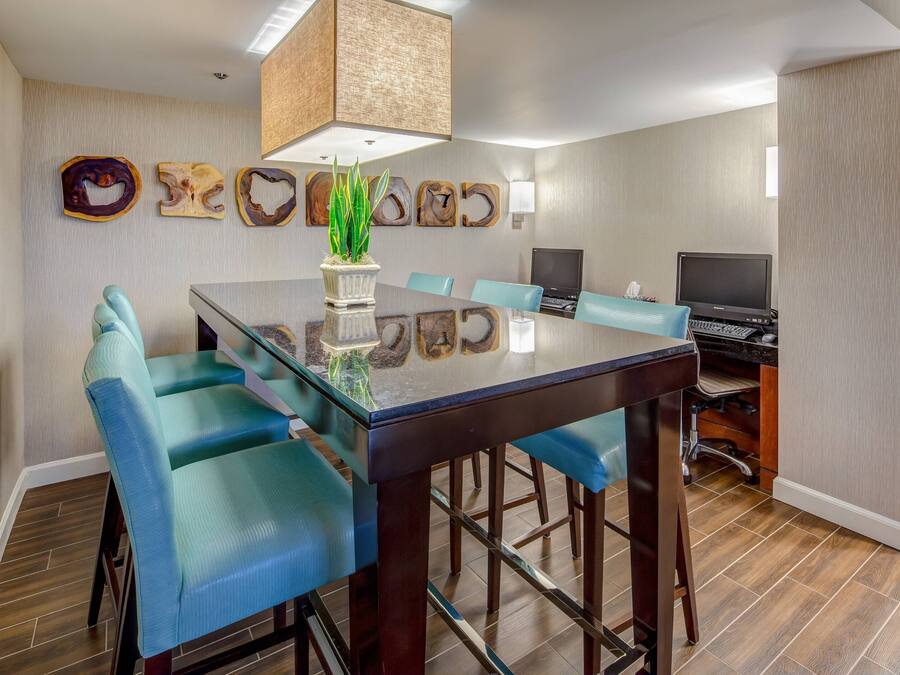 Uma sala de jantar moderna com mesa de vidro, cadeiras azuis e um vaso de planta.