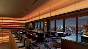Um lobby de hotel moderno com área de bar, assentos e vista para a cidade.