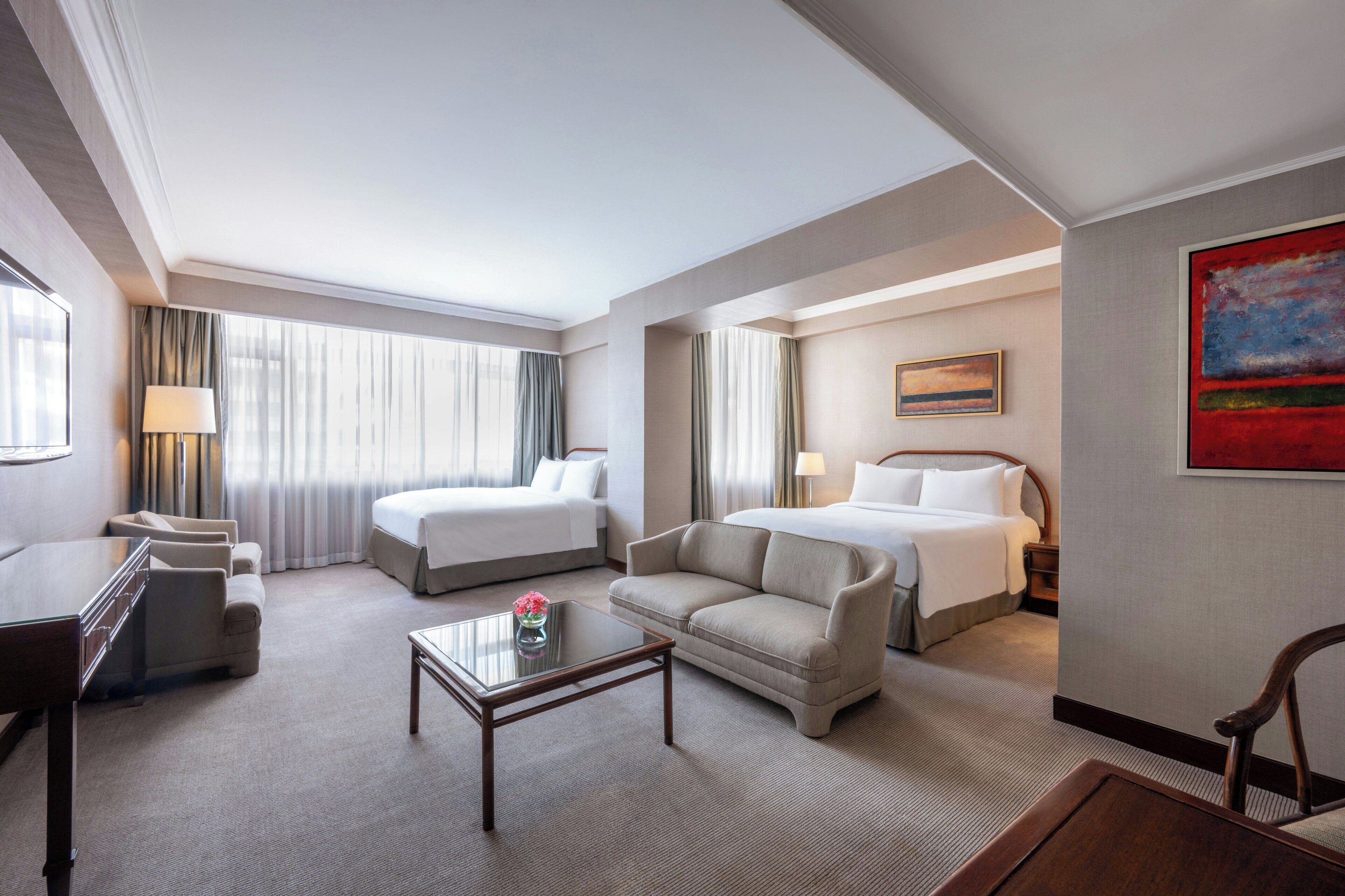 Quarto de hotel com cama, sofá, escrivaninha e cadeira.