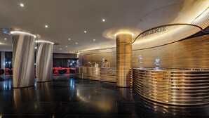 Um hall de hotel moderno com balcão de recepção, área de estar e colunas decorativas.