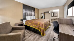 Quarto de hotel com cama, escrivaninha, cadeira, mesa de cabeceira, espelho e vista para a cidade.
