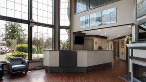 Uma área de recepção com design moderno, incluindo um balcão de atendimento, espaço para assentos e grandes janelas com vista para o exterior.