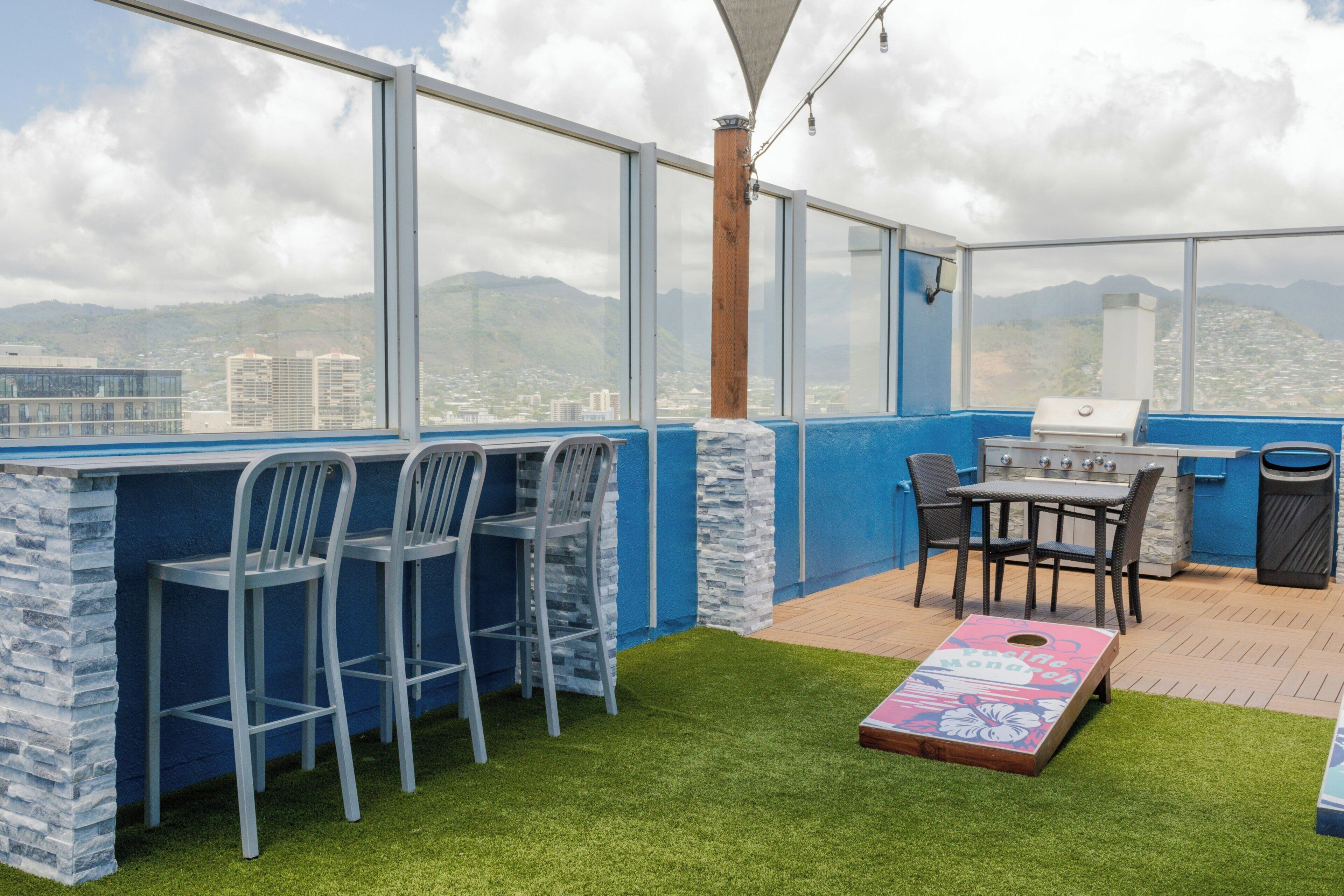 Terraço no telhado com área de churrasco, assentos e vista para a paisagem urbana.