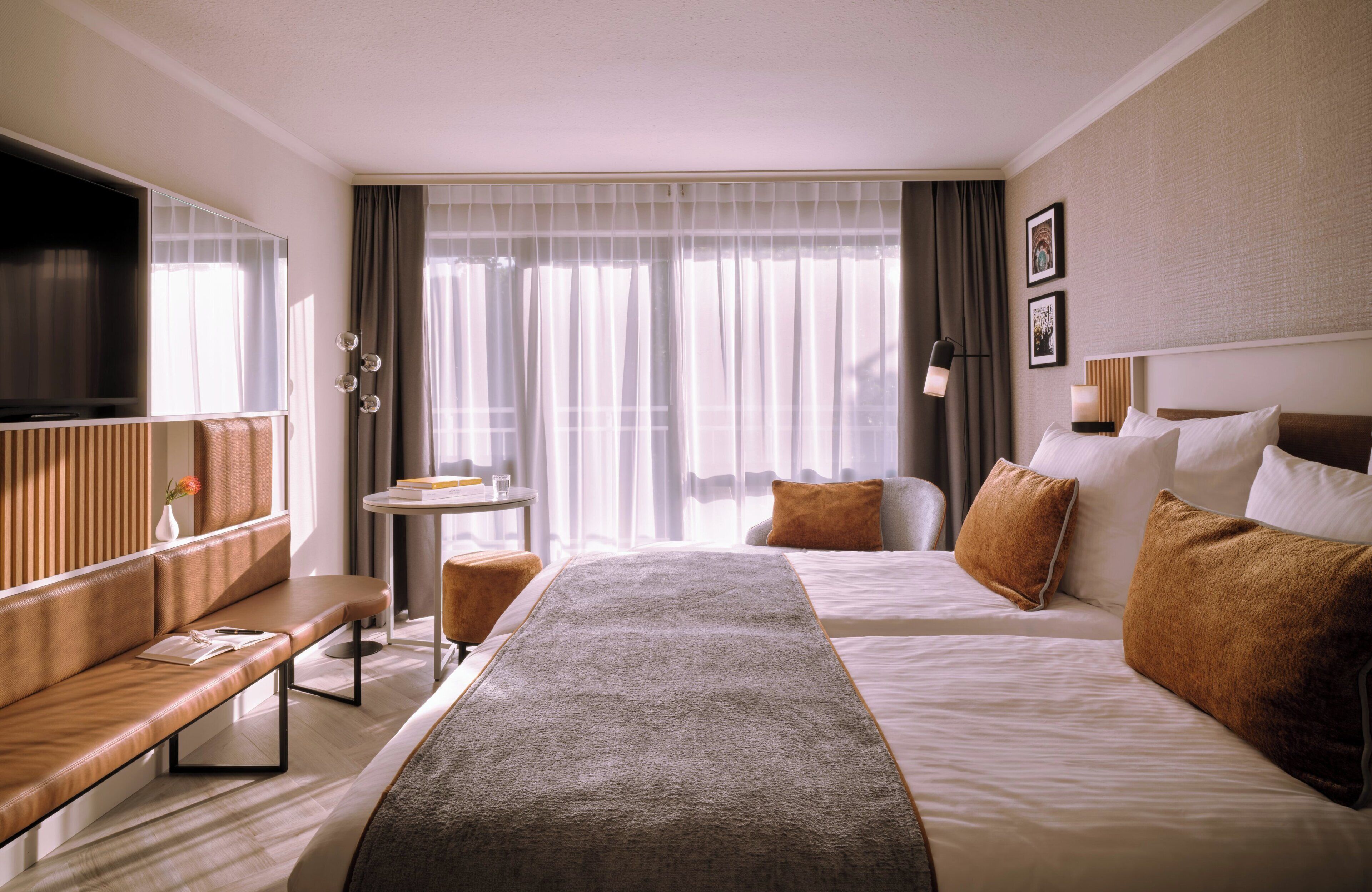 Quarto de hotel com uma cama grande, um sofá, uma mesinha e uma televisão.