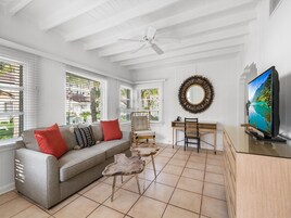 Sala de estar com sofá, mesa de centro, televisão e um espaço de jantar com cadeira e mesa.