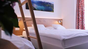Quarto com beliche, mesa de cabeceira, luminária na parede e pintura de uma paisagem montanhosa.