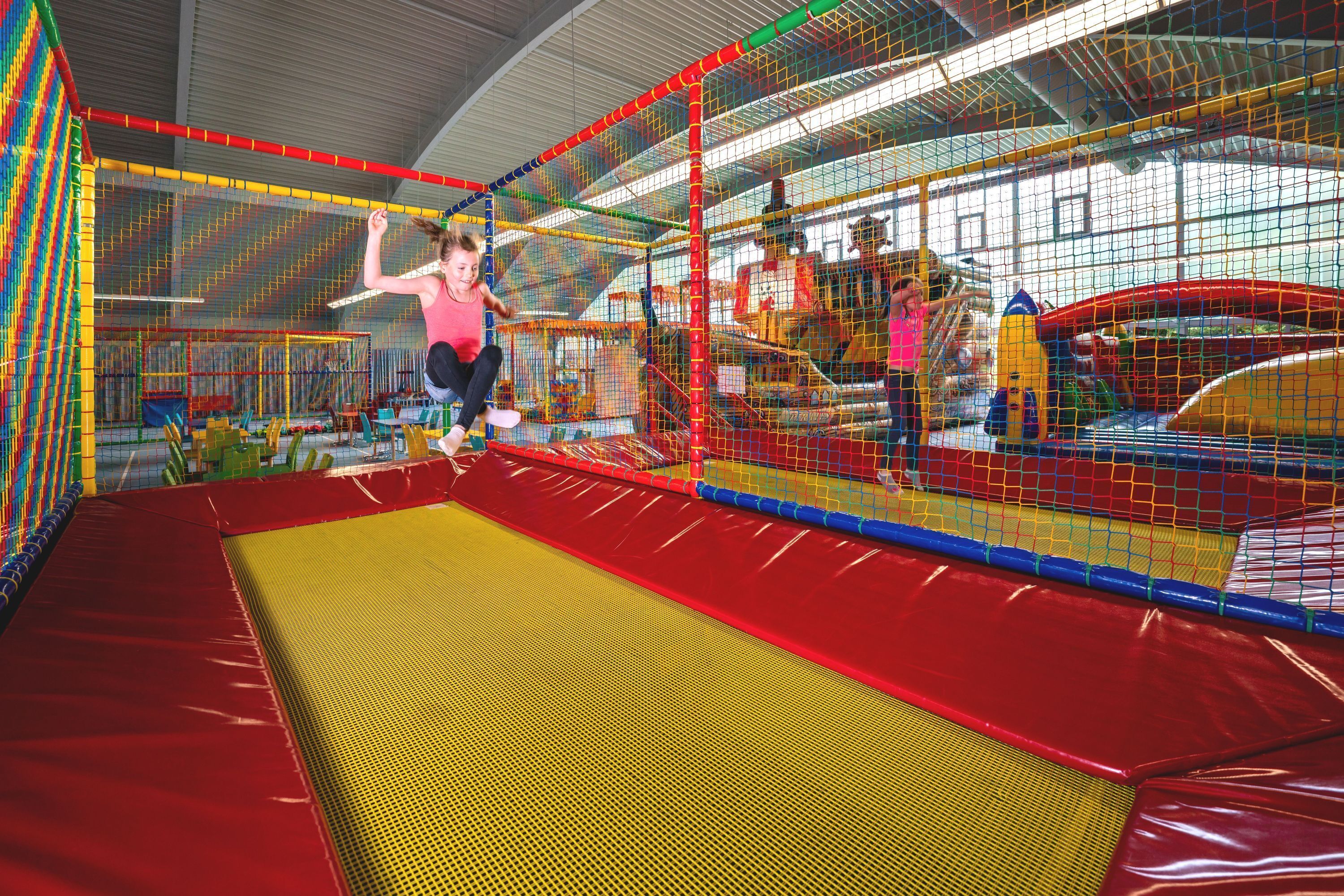 Uma área de recreação interna com um trampolim e estruturas de escalada com redes.