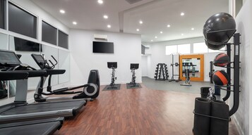 Uma academia com esteiras, bicicletas ergométricas e equipamentos de musculação.