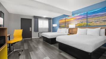 Quarto de hotel com duas camas, uma escrivaninha, uma cadeira, televisão e uma grande pintura de paisagem na parede.