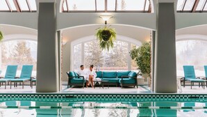 Uma área de piscina com um espaço para sentar e uma planta pendente.
