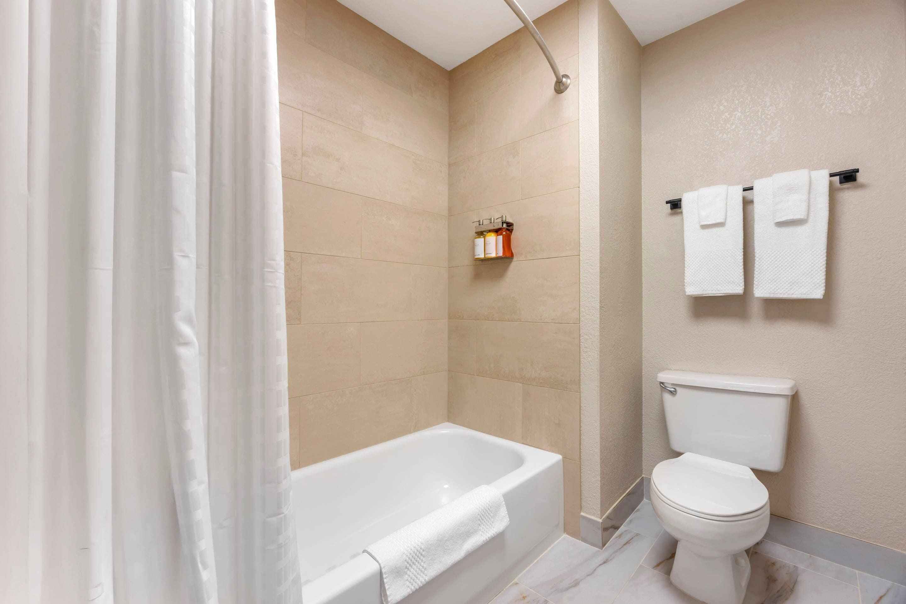 Casa de banho com banheira, sanita e um porta-toalhas com toalhas.