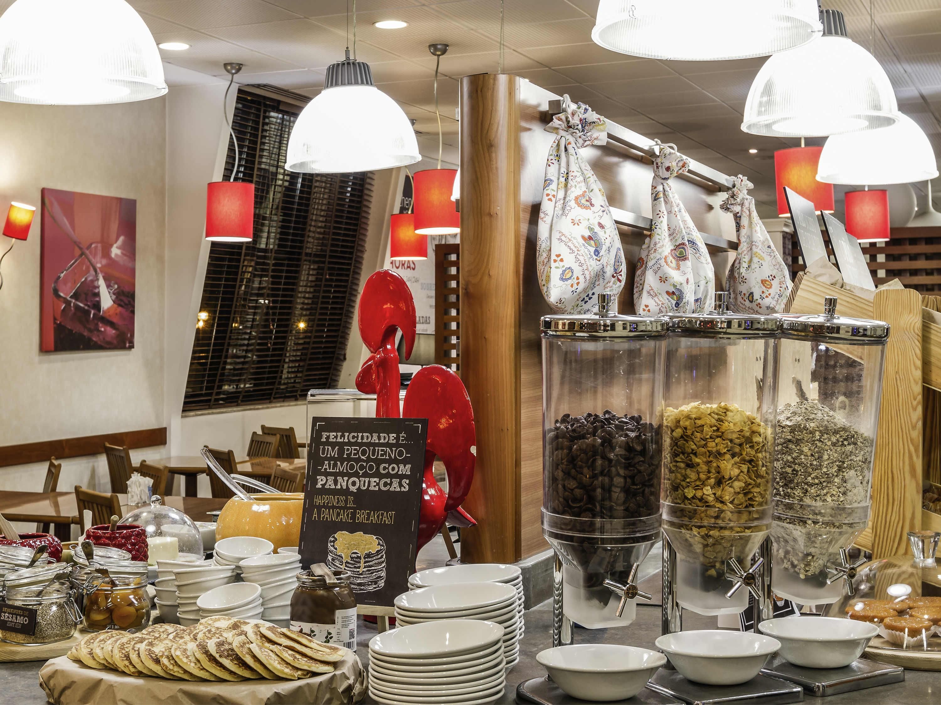 Um buffet de café da manhã com diversos alimentos e um aviso que promove a felicidade através de um pequeno-almoço.
