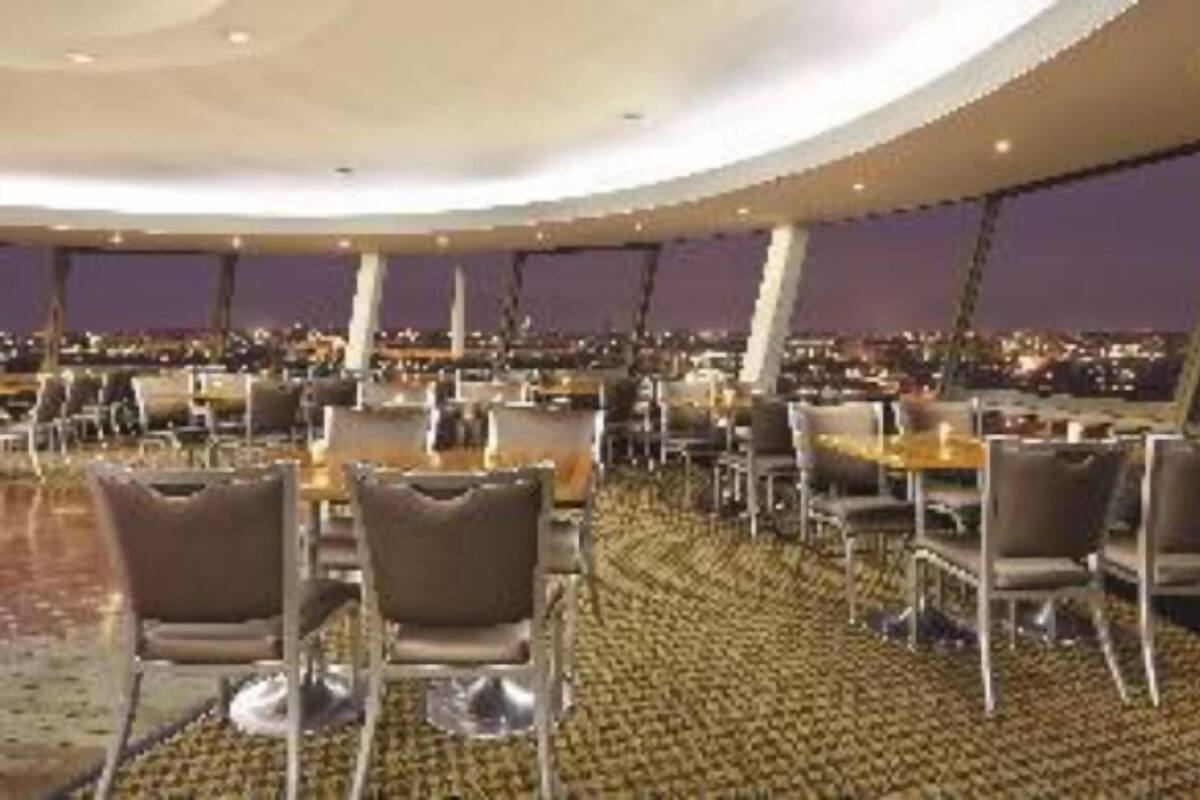 Um restaurante com vista panorâmica da cidade, mesas e cadeiras redondas.