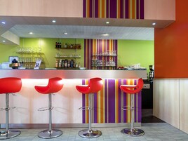 Uma área de bar com balcão, banquetes e prateleiras com garrafas e copos.