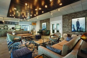 Espaço lounge moderno com sofás, poltronas e um bar de café.