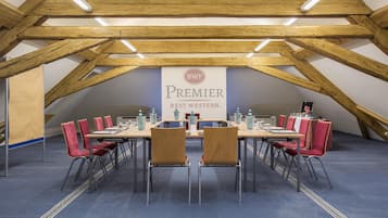 Uma sala de conferências com uma mesa comprida, cadeiras vermelhas e um banner com a inscrição 'Premier Best Western'.