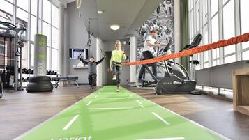 Academia com esteiras, máquina de remo e pista de corrida verde.