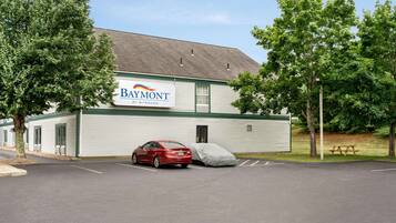 Um motel Baymont com um carro vermelho estacionado em frente.