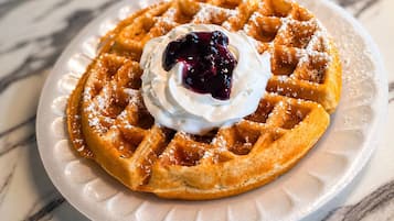 Waffle com chantilly e compota de frutas vermelhas em um prato.