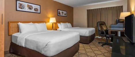 Quarto de hotel com duas camas, uma escrivaninha, uma cadeira e uma televisão.
