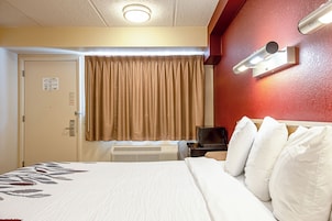 Quarto de hotel com cama, televisão, aquecedor e porta com aviso.