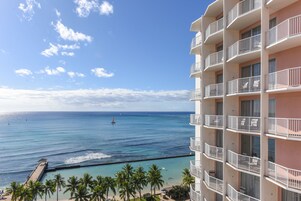 Hotel alto com várias varandas com vista para uma praia e oceano.
