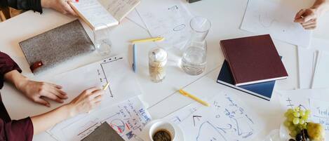 Uma reunião com documentos, laptops e uma xícara de café sobre uma mesa.