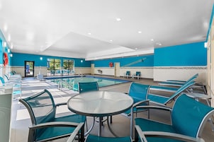 Uma área de piscina com espreguiçadeiras e uma mesa, uma porta que dá para o exterior e uma parede azul.