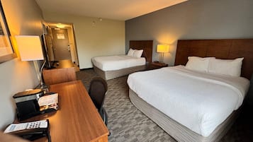 Quarto de hotel com duas camas, uma mesa com telefone e uma cadeira.