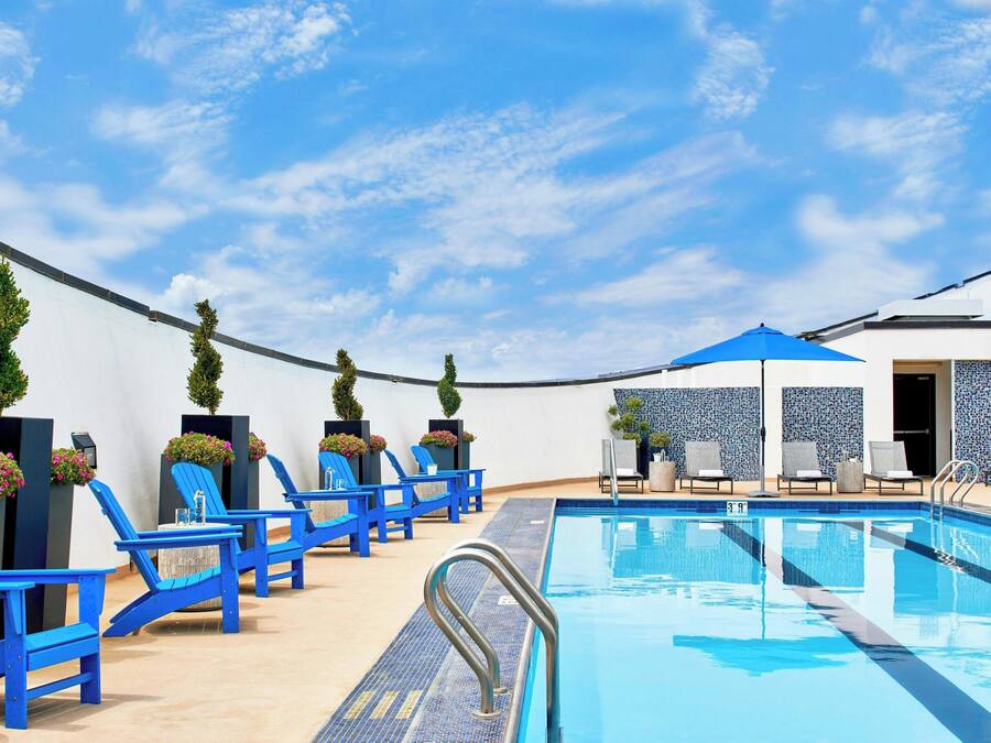 Área da piscina com cadeiras azuis e um tanque.
