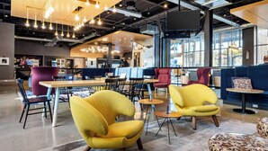 Um café moderno com cadeiras amarelas, área de bar e grandes janelas.