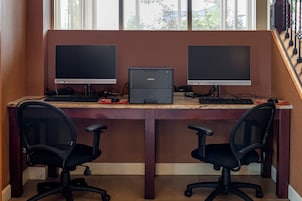 Um espaço de trabalho com dois monitores, um computador de mesa e duas cadeiras de escritório.