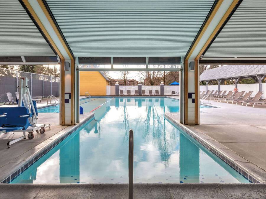 Uma piscina coberta com água cristalina, uma cadeira de salva-vidas e espreguiçadeiras.