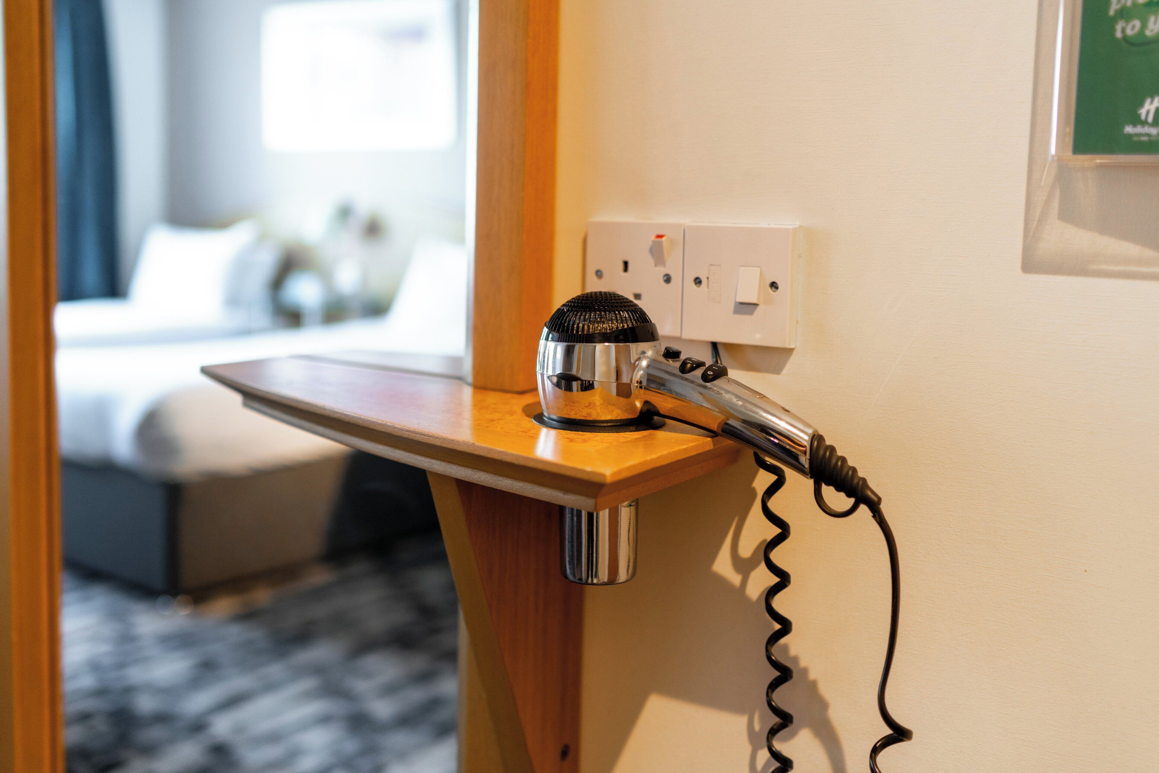 Um secador de cabelo conectado a uma tomada em um quarto de hotel.