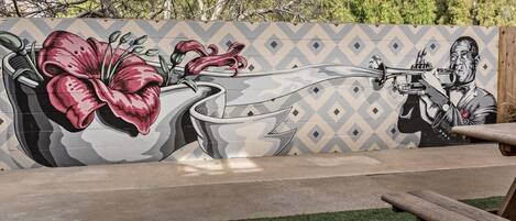 Um mural com um homem tocando trompete e uma flor grande.