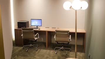 Uma sala de conferências com duas cadeiras de escritório, uma mesa com computador e um abajur.