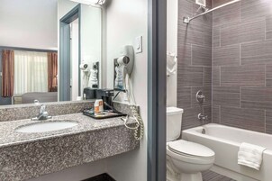 Uma casa de banho moderna com lavatório de bancada em granito, secador de cabelo e banheira.