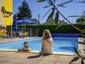 Uma área de piscina com piscina azul, um sinal amarelo e mobiliário de área externa.