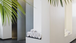 Um lobby moderno com uma mesa de recepção, uma área de estar com toalhas e uma grande planta em vaso.