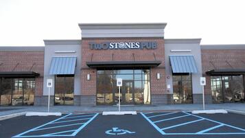 Um edifício com uma placa indicando 'Two Stones Pub' e vagas de estacionamento sinalizadas com o símbolo de acessibilidade para cadeiras de rodas.