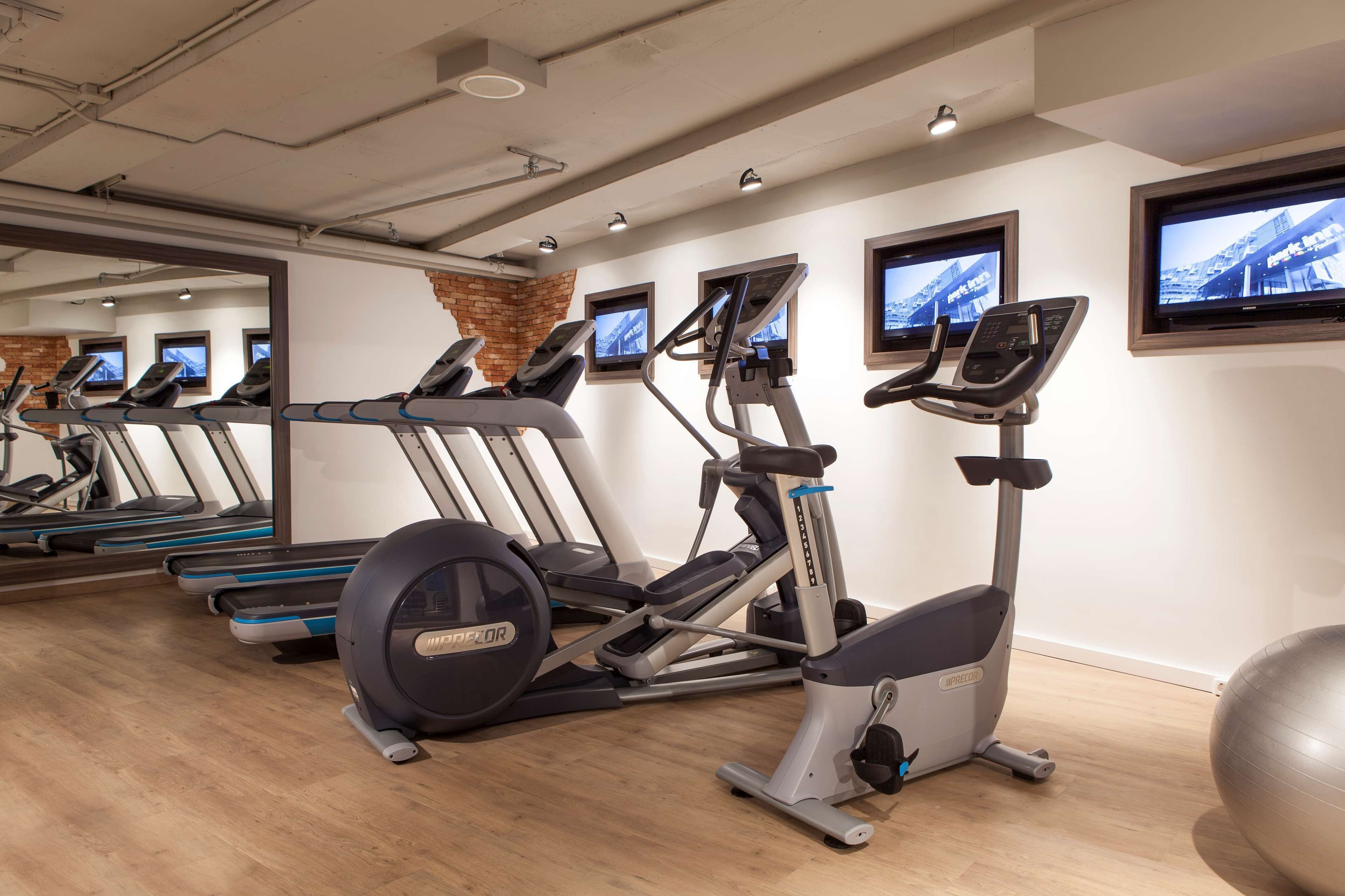 Uma academia com esteiras, elípticos e bolas de exercício.