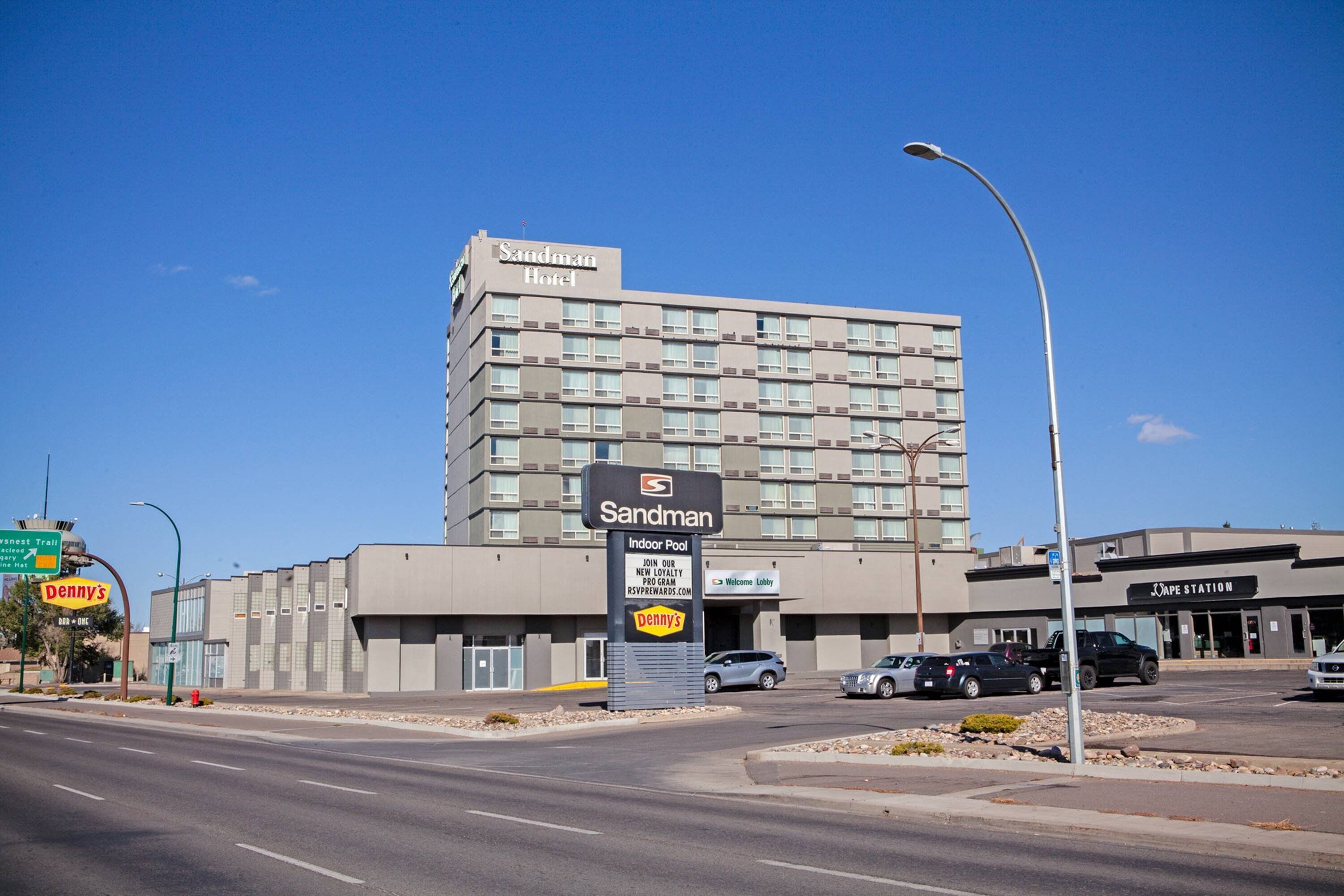 Um hotel com a placa Sandman Hotel e a placa Denny's.