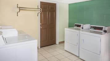 Uma lavanderia com uma porta, um varal e duas pilhas de máquinas de lavar e secar.