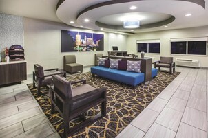 Um saguão de hotel com um sofá azul, área de estar e balcão de recepção.