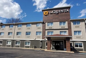 Um hotel La Quinta com design moderno, apresentando um sol em destaque, várias janelas e um estacionamento à frente.