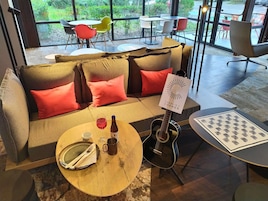 Uma área de estar aconchegante com um sofá, uma mesa de centro, um violão e uma placa que indica 'Charlie's Corner'.