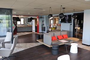 Uma área de estar moderna com sofá, cadeiras, uma mesa pequena e um bar ao fundo.