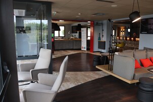 Um interior moderno com área de bar, assentos e cozinha ao fundo.