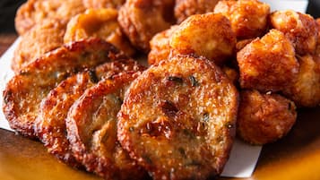 Um prato com diversos alimentos fritos, provavelmente bolinhos ou croquetes, com uma crosta dourada.